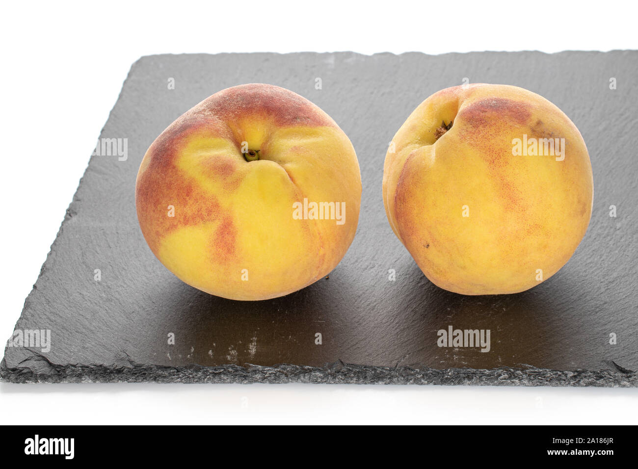 Group of two whole fresh fuzzy peach on grey stone isolated on white ...