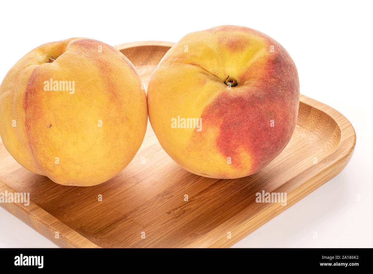 Group of two whole fresh fuzzy peach on wooden square plate isolated on ...