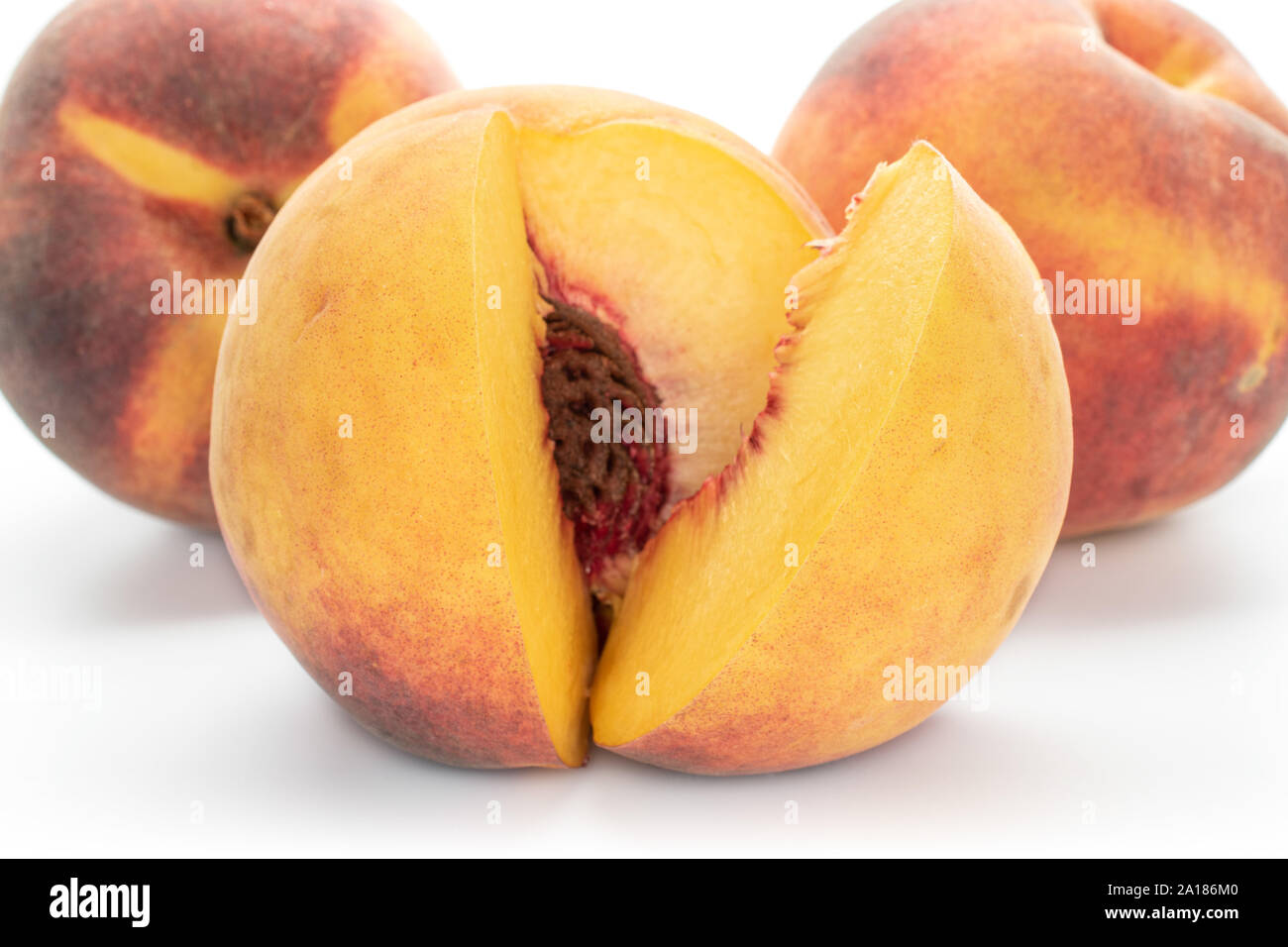 Group of three whole fresh fuzzy peaches one sliced isolated on white ...