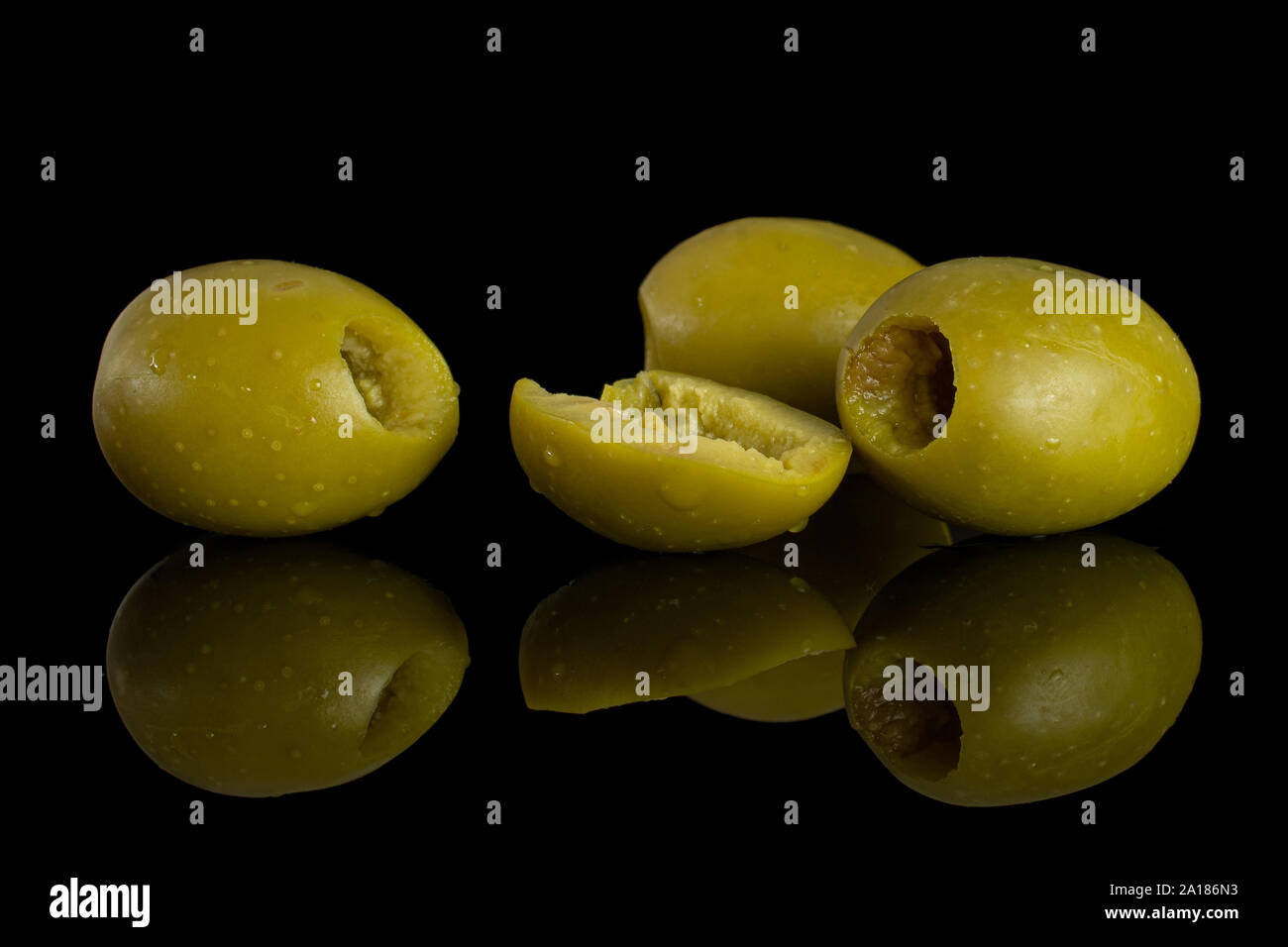 Group of three whole one half of pitted green olive isolated on black ...