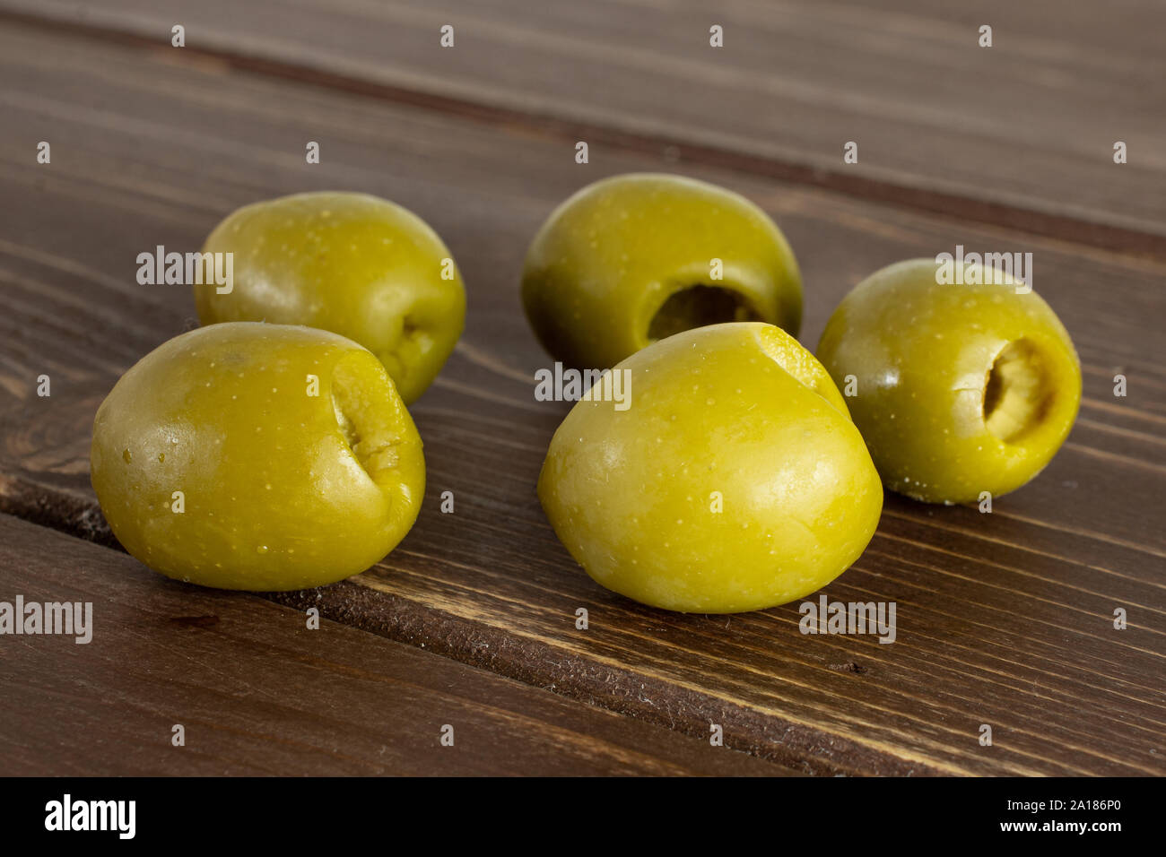 Group of five whole pitted green olive on brown wood Stock Photo - Alamy