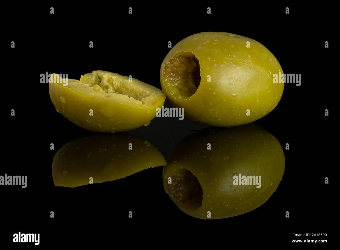 Group of one whole one half of pitted green olive isolated on black ...