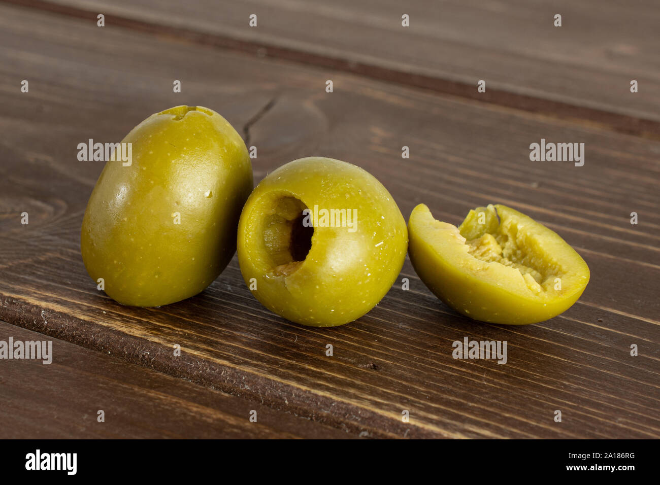 Group of two whole one half of pitted green olive on brown wood Stock ...