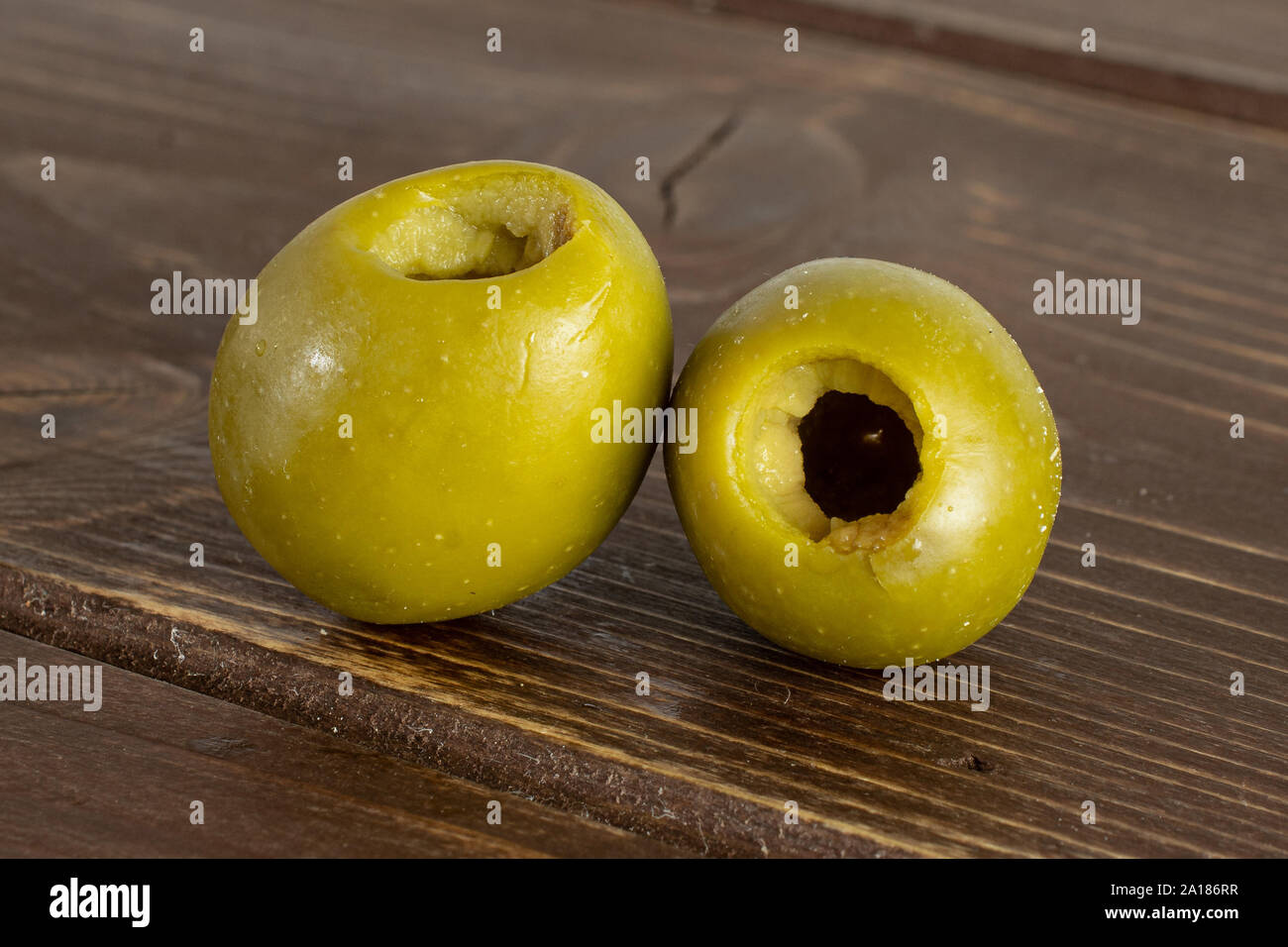 Group of two whole pitted green olive on brown wood Stock Photo - Alamy