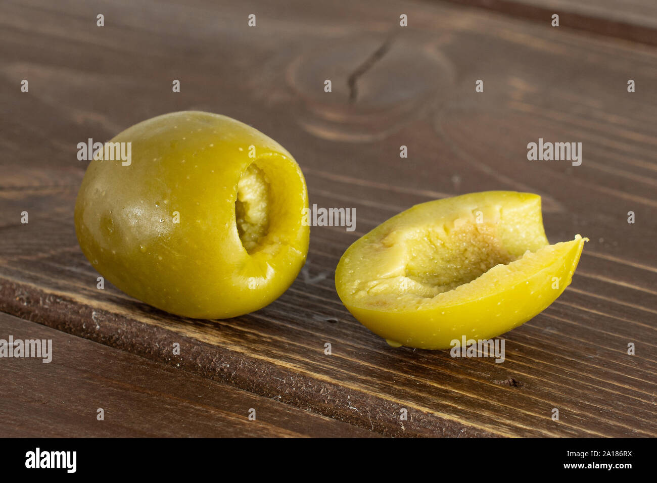Group of one whole one half of pitted green olive on brown wood Stock ...