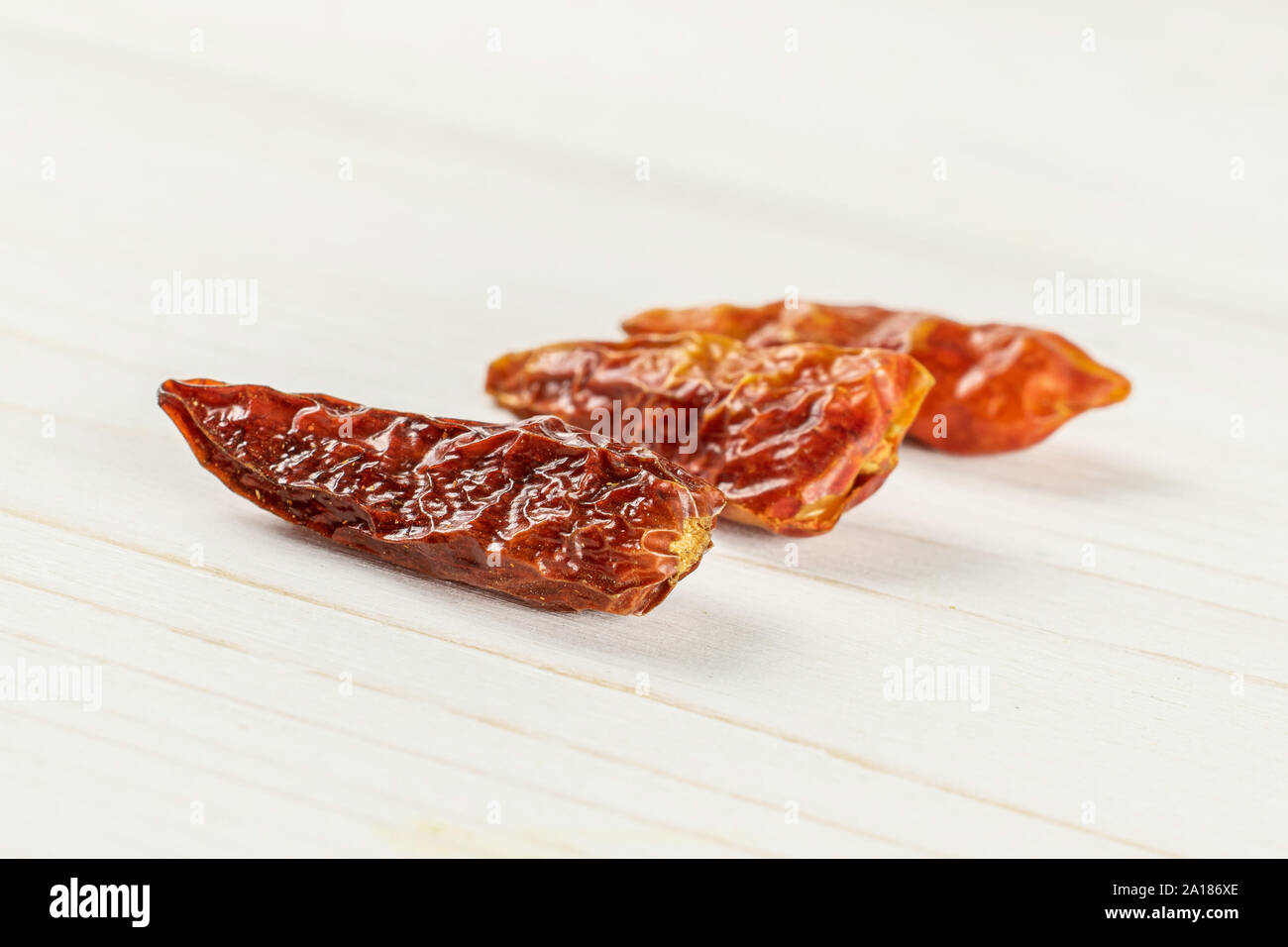Group of three whole dry red chili pepper peperoncino in row on white ...
