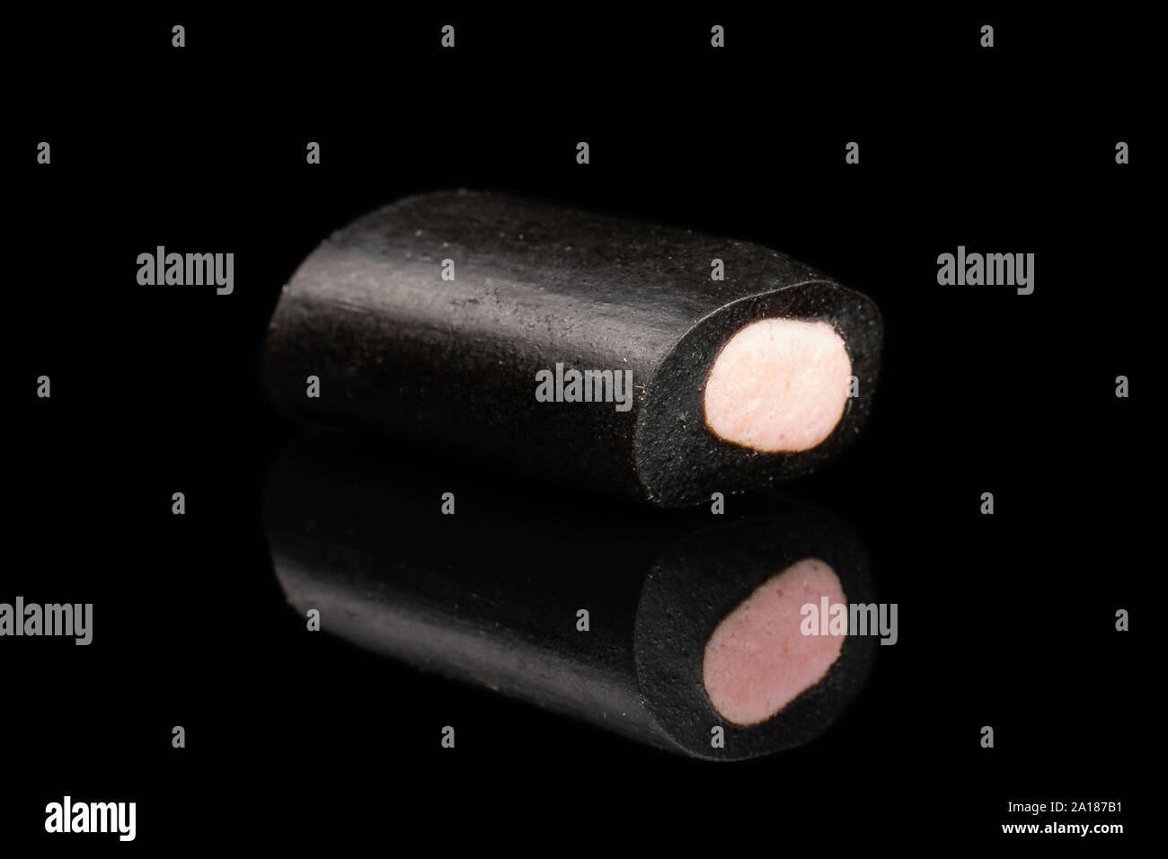 One whole sweet black liquorice candy isolated on black glass Stock ...