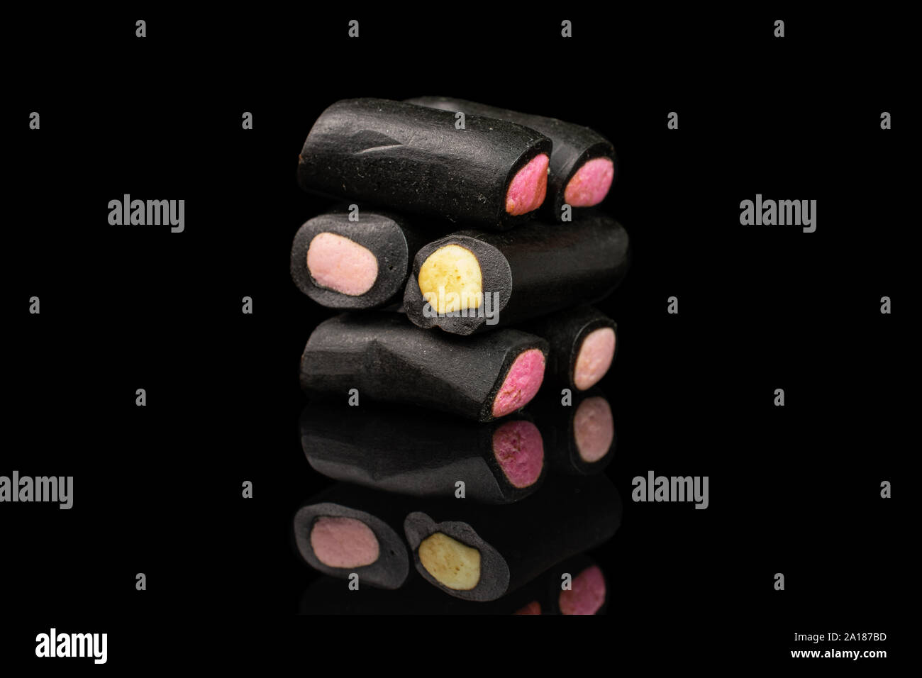 Group of six whole sweet black liquorice candy isolated on black glass ...