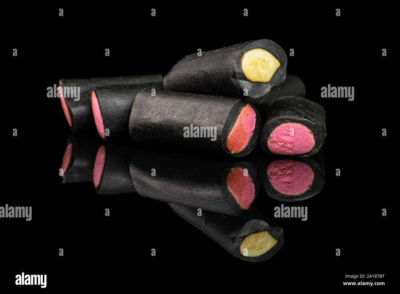 Group of five whole sweet black liquorice candy isolated on black glass ...