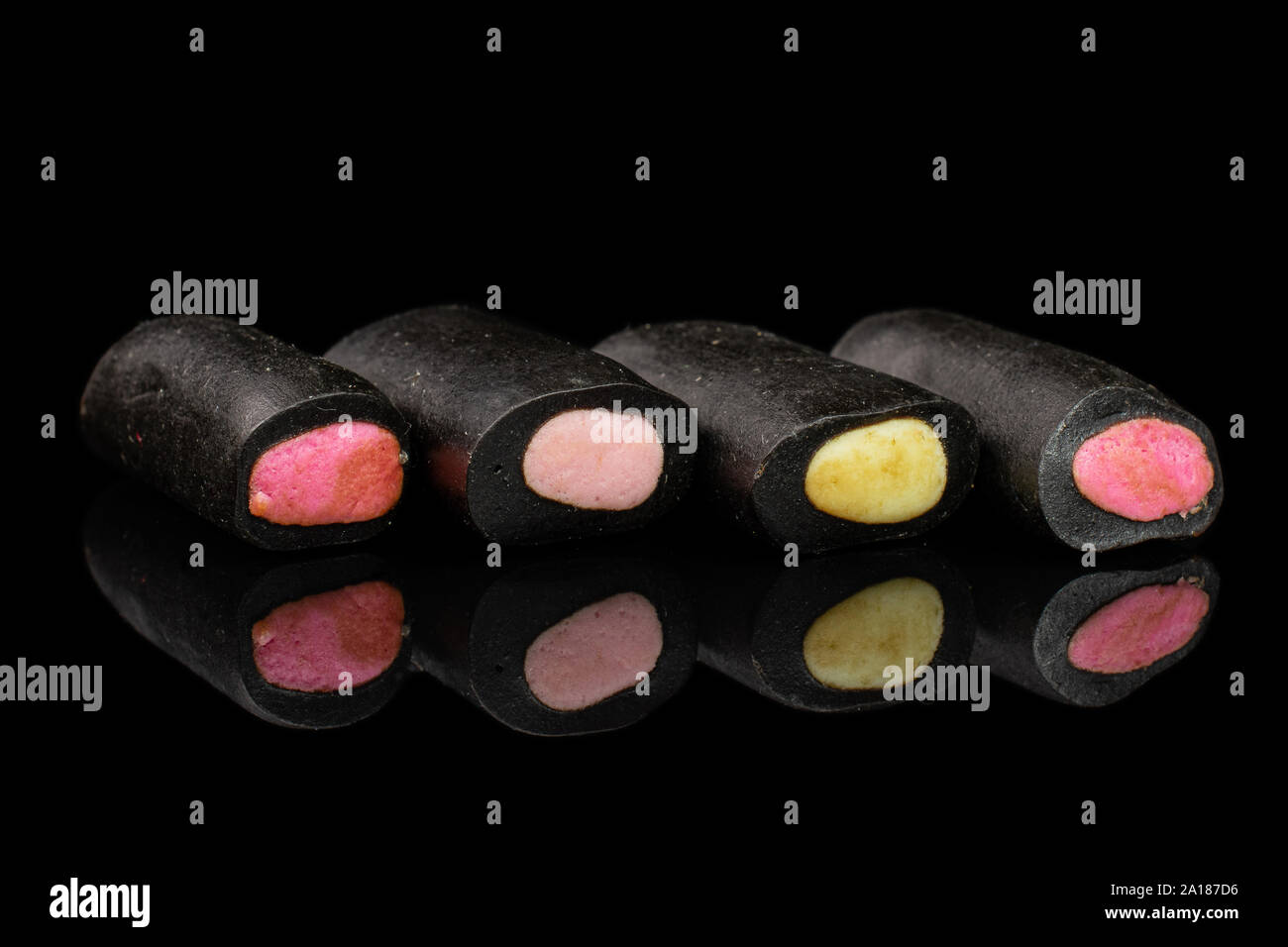 Group of four whole sweet black liquorice candy isolated on black glass ...