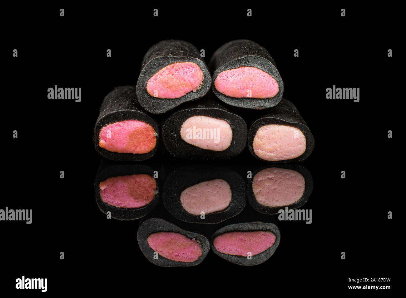Group of five whole sweet black liquorice candy isolated on black glass ...