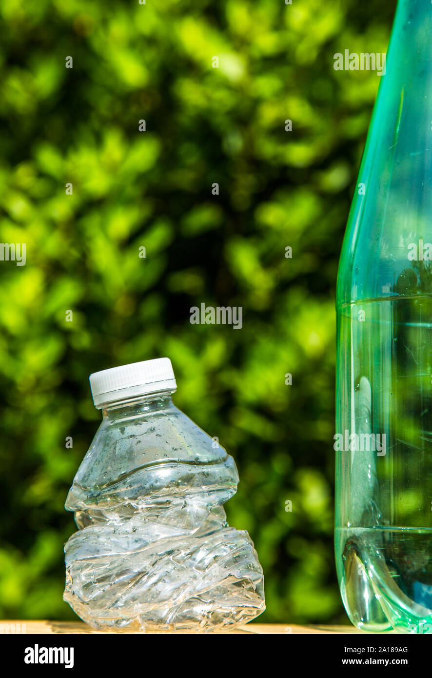 Two plastic bottles with one bottle crushed to illustrate recycling ...