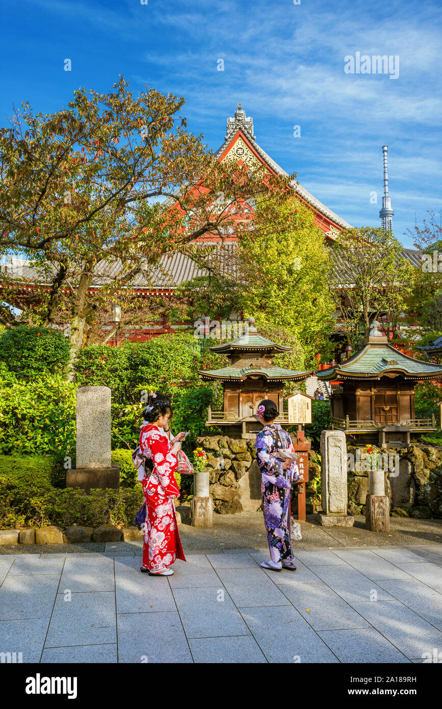 Tokyo between tradition and modernity. Young japanese girls wearing kimons and holding mobile ...