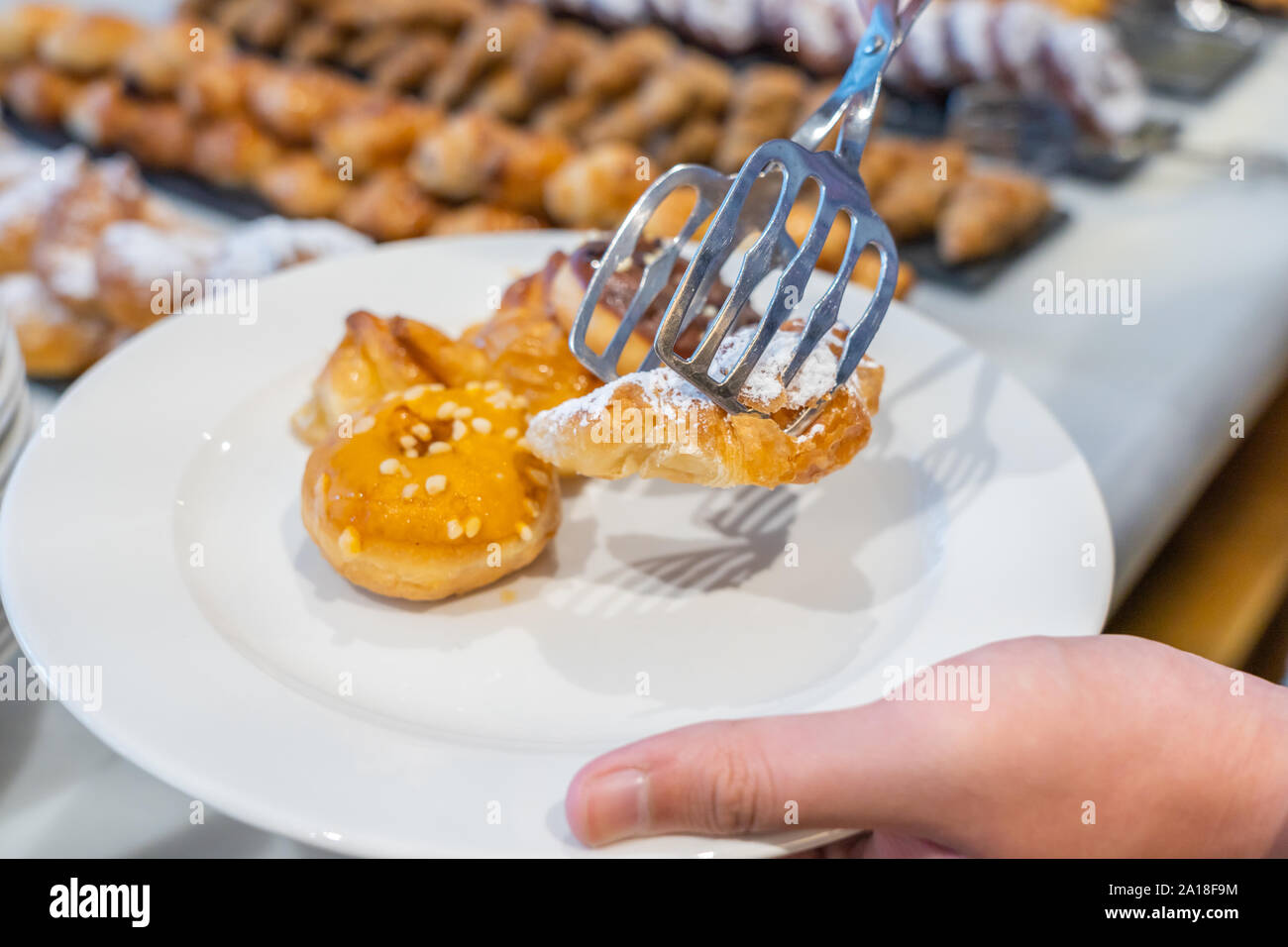 Closeup photo of human hand selecting pastry at breakfast buffet Stock ...
