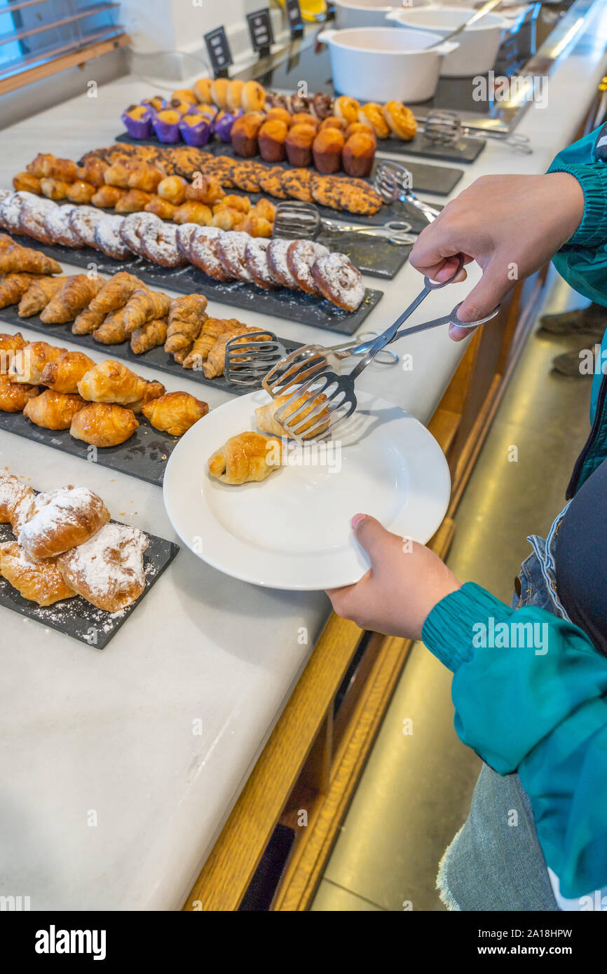 Woman using tongs and picking croissant at pastry buffet counter Stock ...