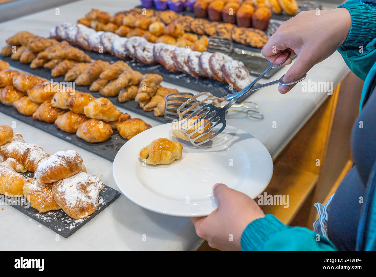 Human hand picking croissant pastry into platter at buffet meal Stock ...