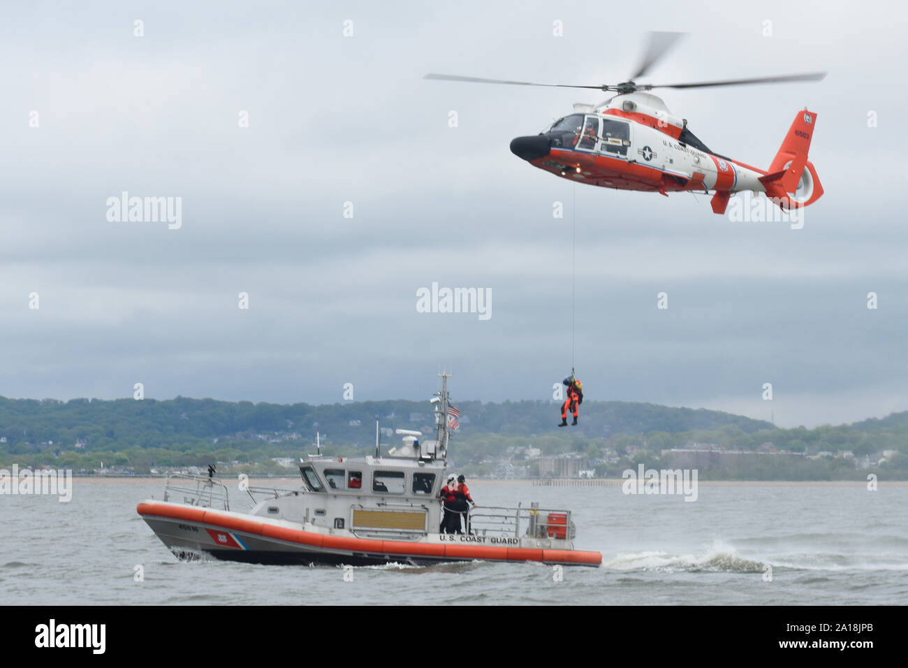 A Coast Guard MH-65 Dolphin helicopter hoists a rescue swimmer from the ...
