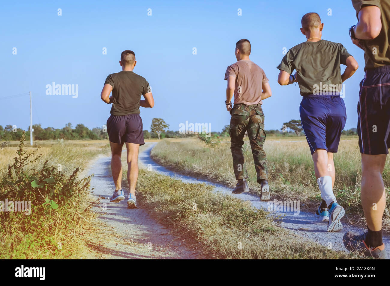 Back view of men running and exercising with friends together on the ...
