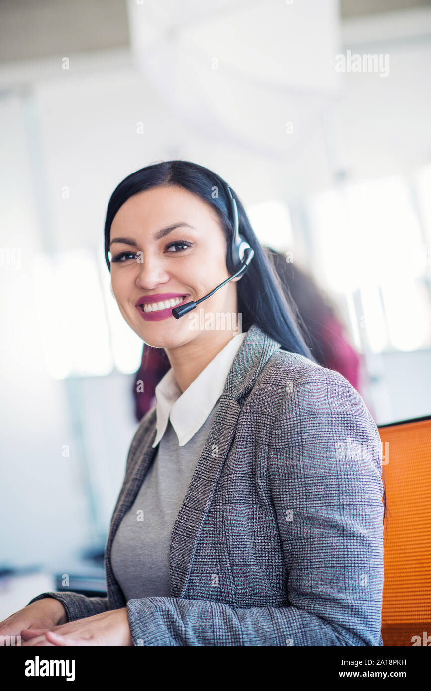 Beautiful business people in headsets are using computers and smiling ...