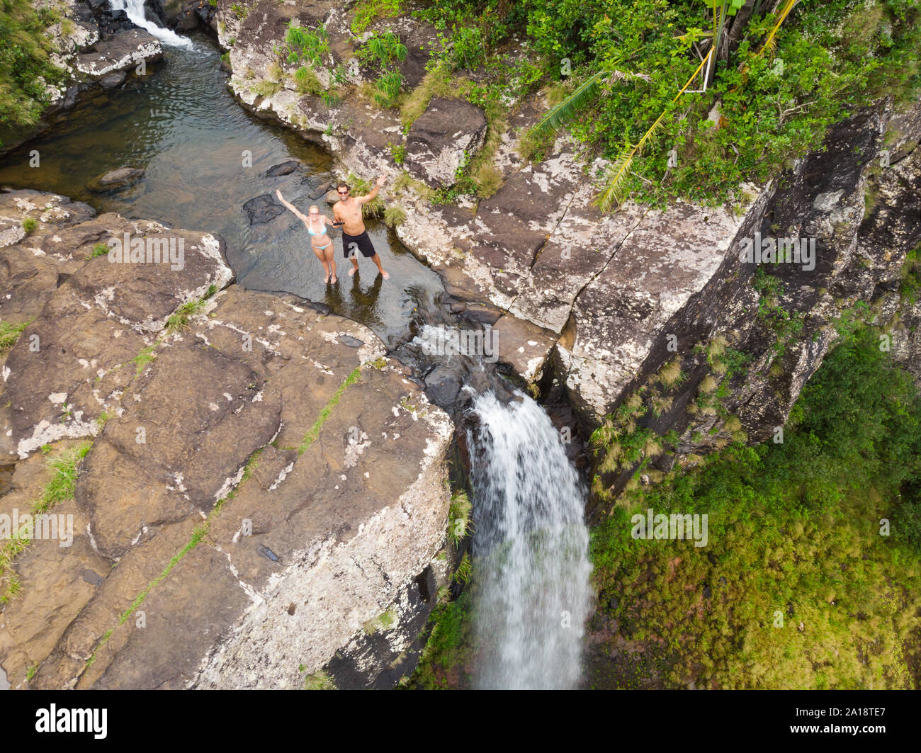 Aerial top view of travel couple waving to drone, standing on the edge ...