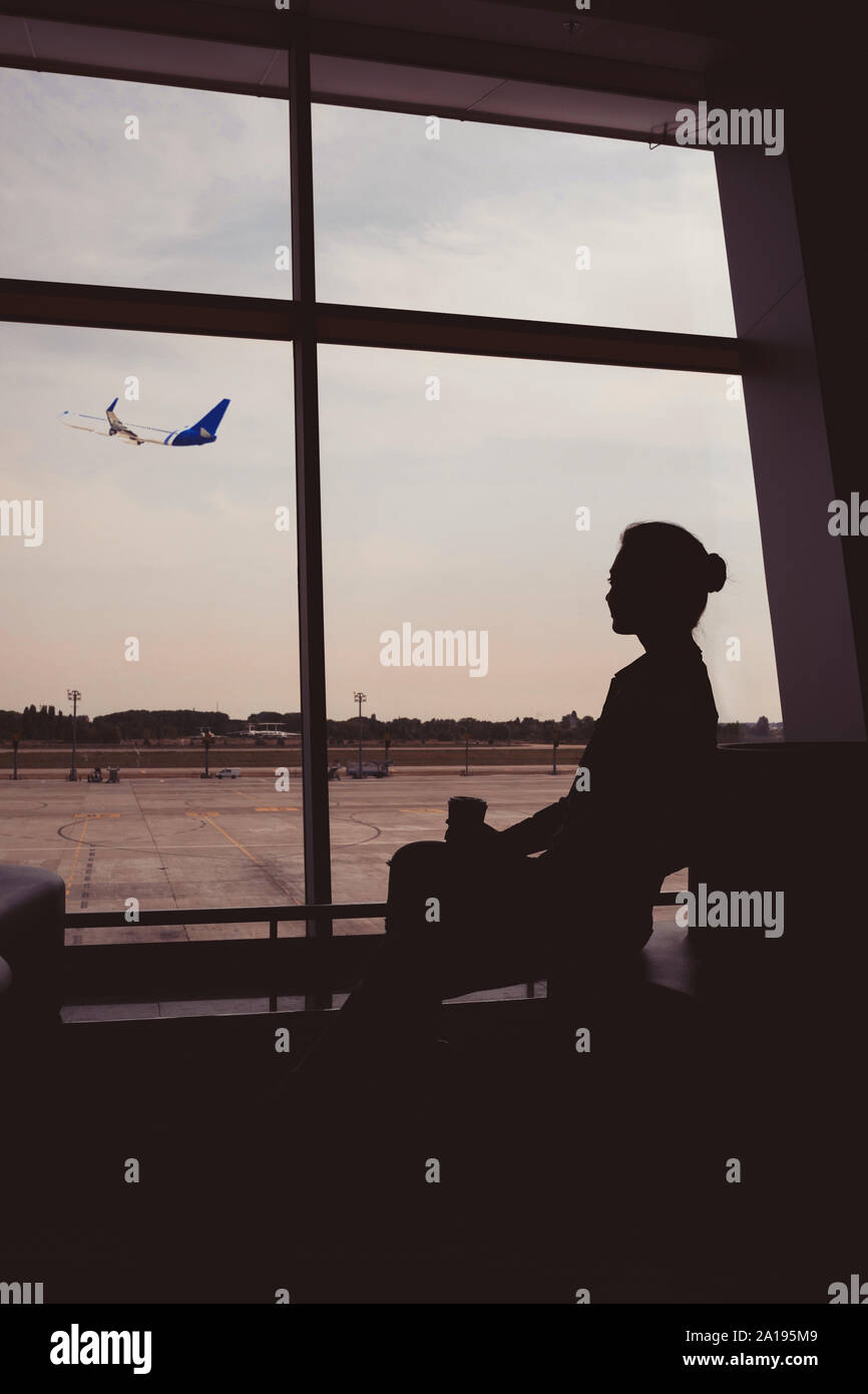 silhouette of woman waiting for flight aircraft. Airline passenger girl ...