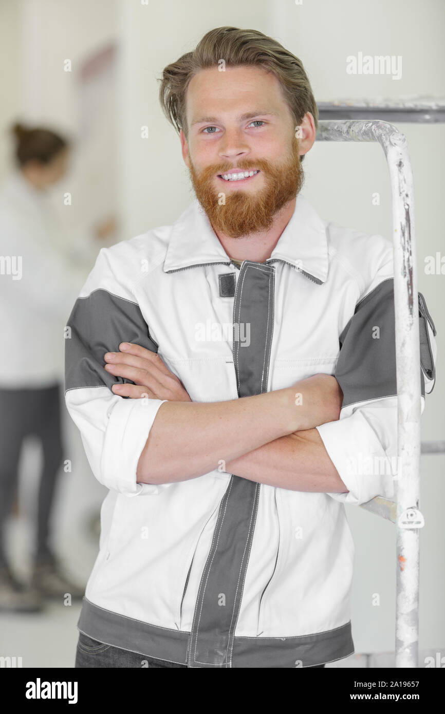 confident smiling painter with white overalls posing with arms crossed ...