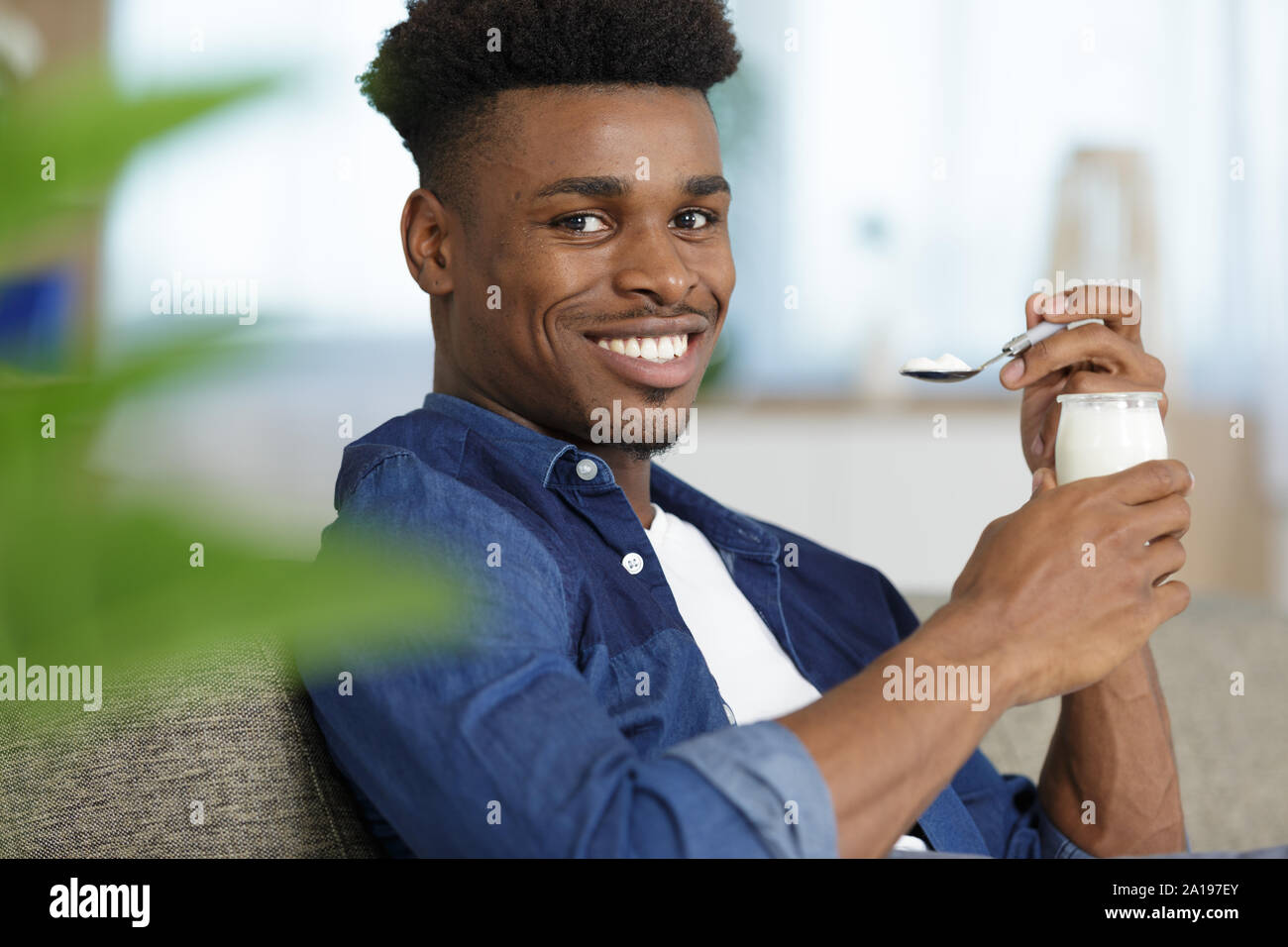 smiling young man eating yogurt Stock Photo - Alamy