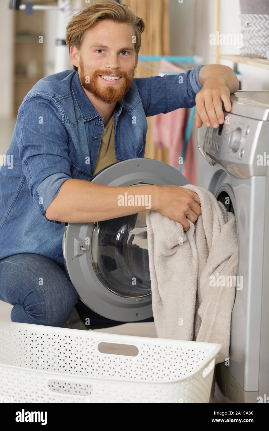 young man putting laundry in washing machine Stock Photo - Alamy