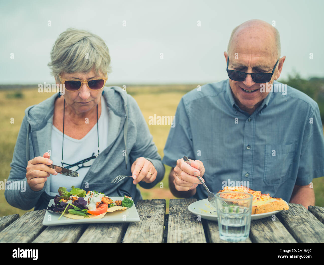 A senior couple are eating their lunch at a picnic table outdoors Stock ...