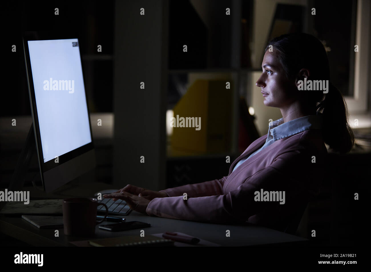 Young businesswoman sitting at her workplace in front of computer ...