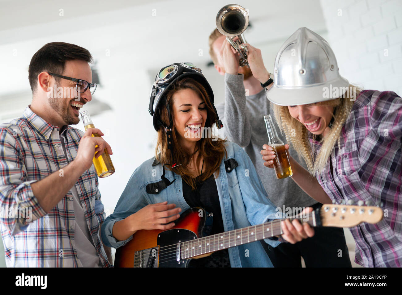 Group of young friends having fun together and playing in music band ...