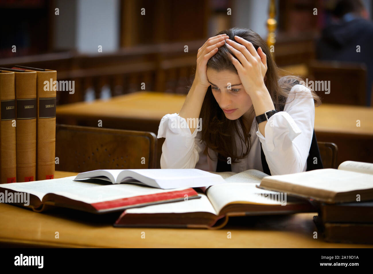 Overloaded student in library Stock Photo - Alamy