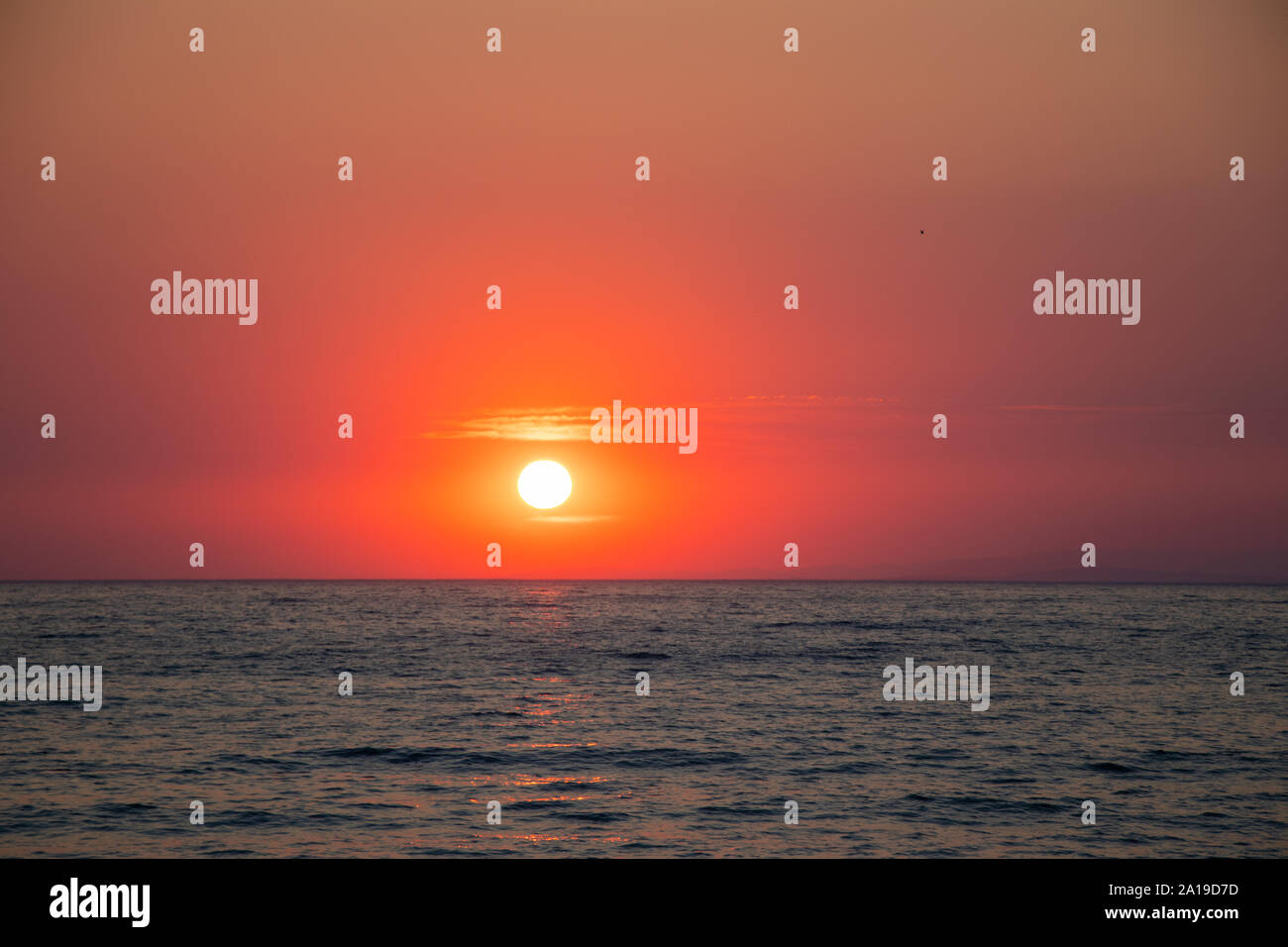 Golden hour at sunset with the sun hiding behind the sea Stock Photo ...