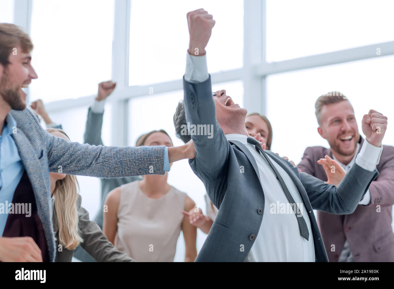 group of cheerful company employees congratulating their colleague ...