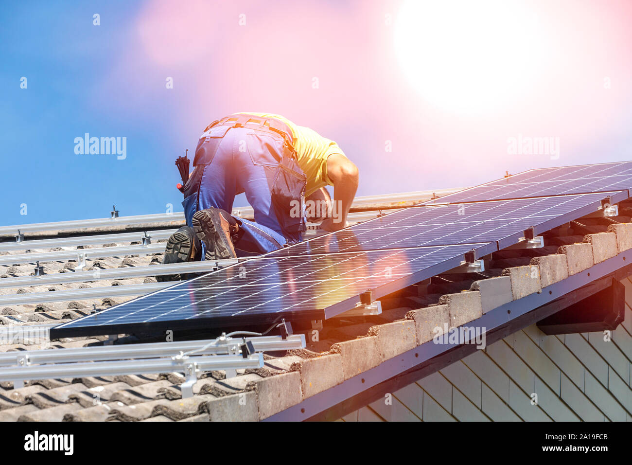 Installing solar photovoltaic panel system. Solar panel technician installing solar panels on ...