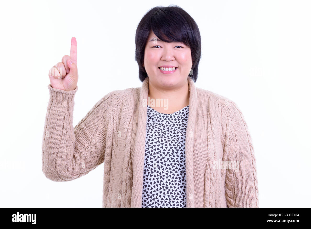 Happy overweight Asian woman pointing up ready for winter Stock Photo ...