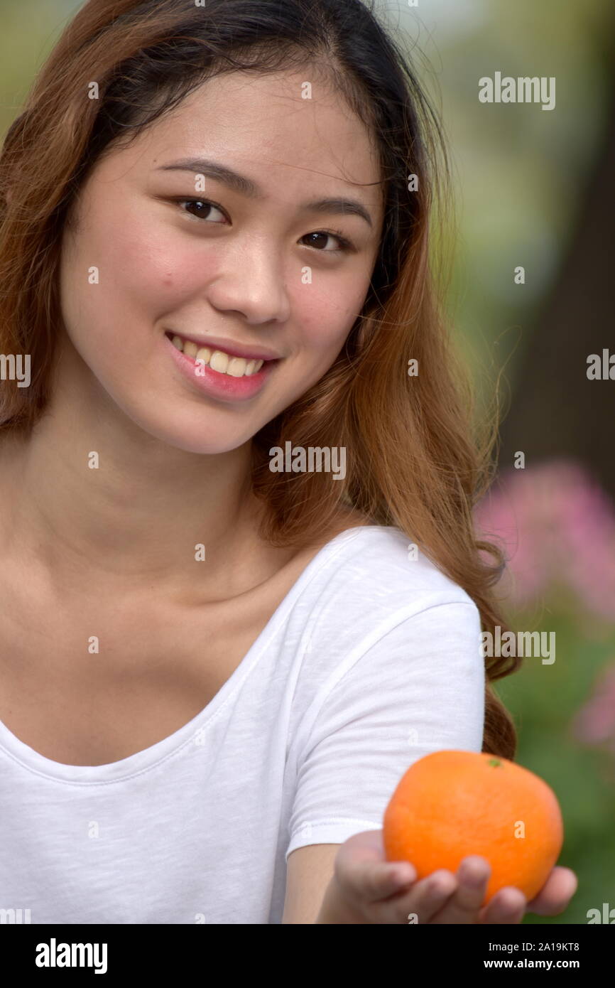 Attractive Female Smiling With An Orange Stock Photo - Alamy