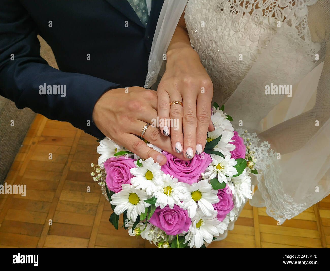 Wedding ring and two hands together over a pink bouquet. Love couple ...