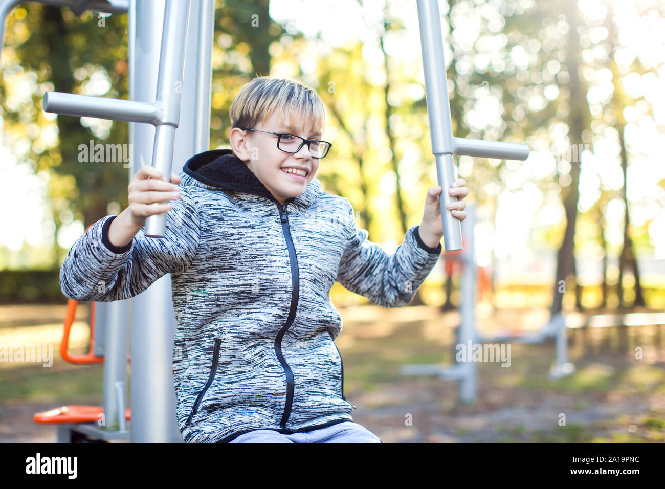 Smart kid boy does workout on trainer equipment outdoor. Children ...