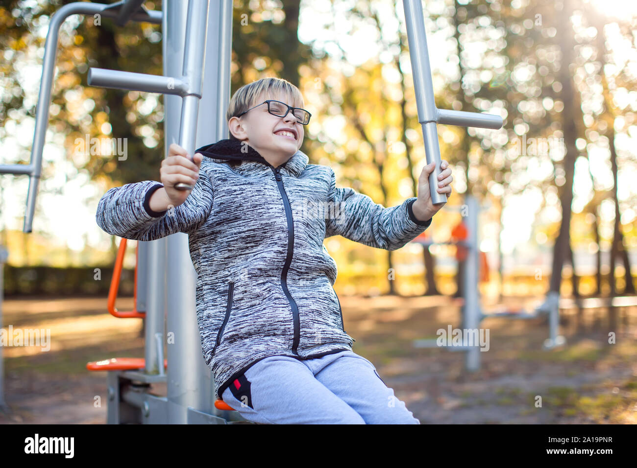 Smart kid boy does workout on trainer equipment outdoor. Children ...