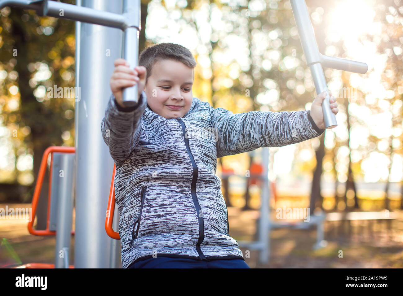 Kid boy does workout on trainer equipment outdoor. Children, activity ...