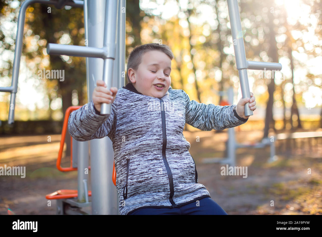 Kid boy does workout on trainer equipment outdoor. Children, activity ...
