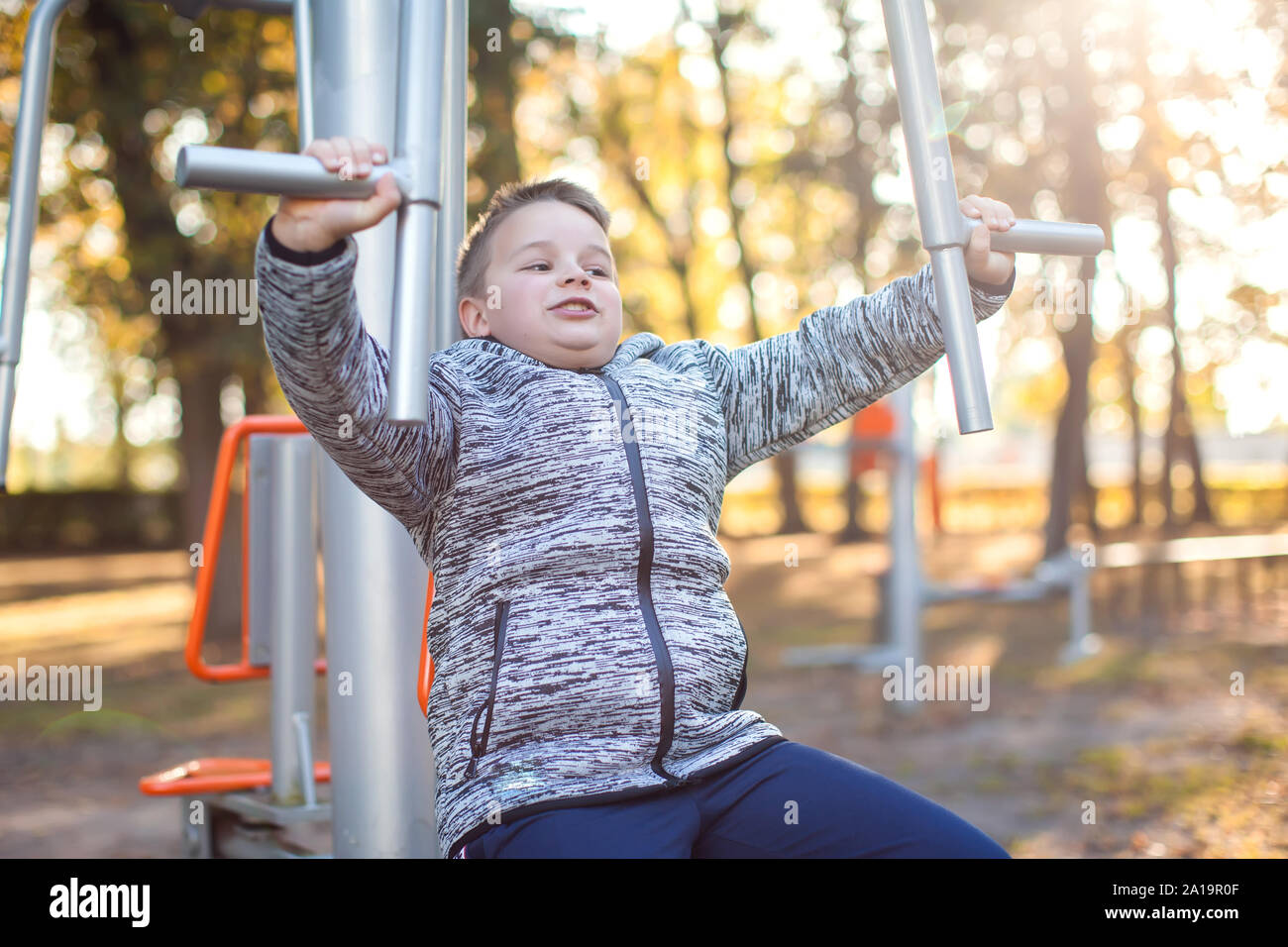 Kid boy does workout on trainer equipment outdoor. Children, activity ...