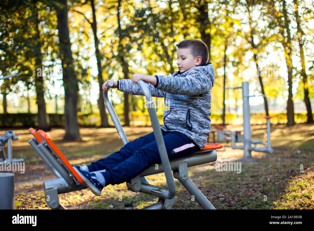 Kid boy does workout on trainer equipment outdoor. Children, activity ...