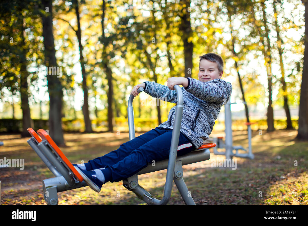 Kid boy does workout on trainer equipment outdoor. Children, activity ...