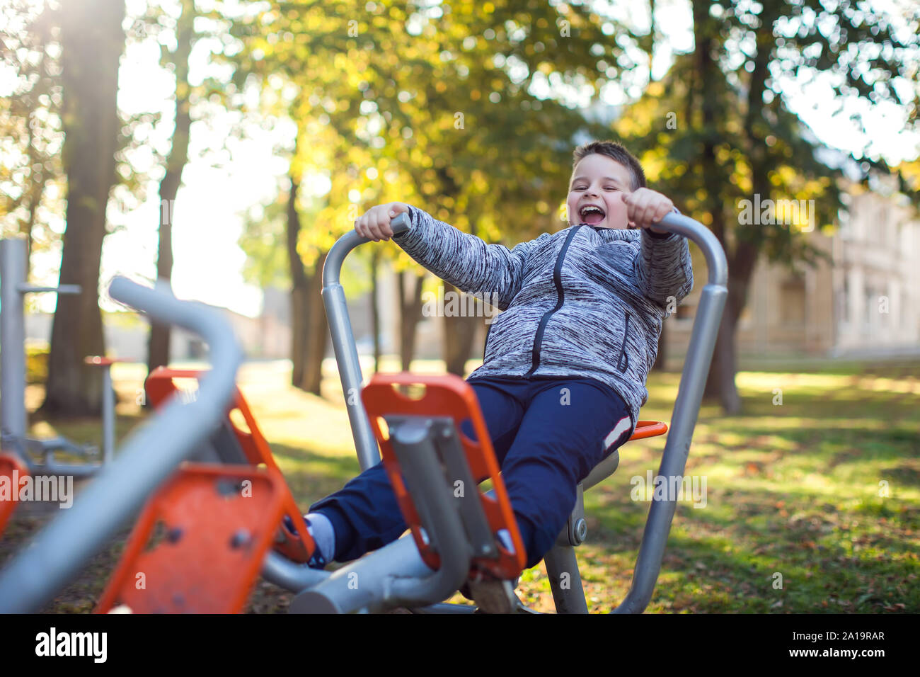 Kid boy does workout on trainer equipment outdoor. Children, activity ...