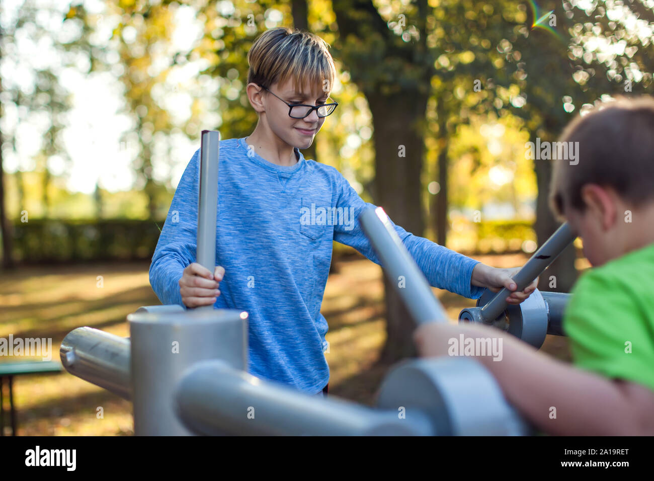 Two boys do workout on trainer equipment outdoor. Children, activity ...
