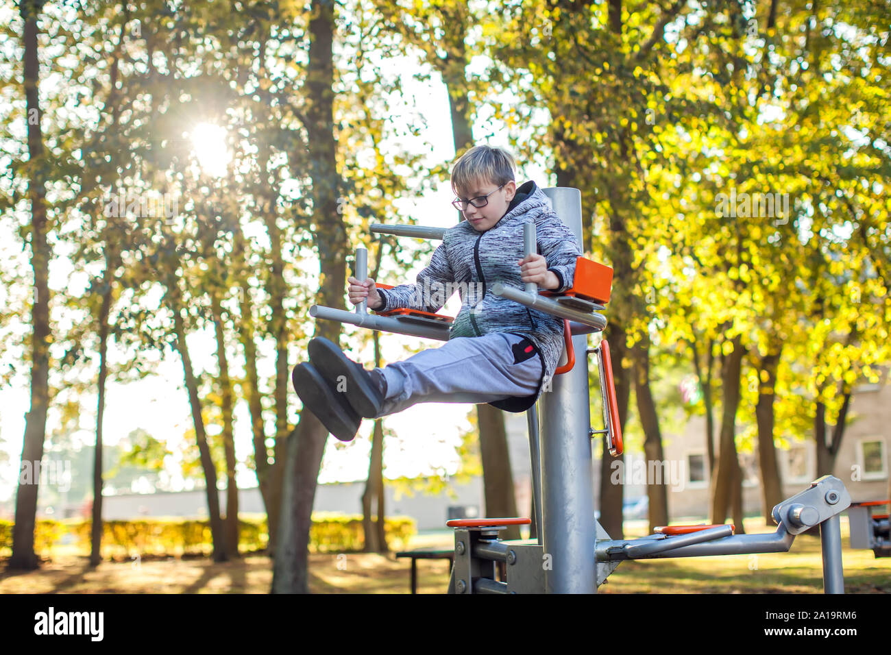 Kid boy does workout on trainer equipment outdoor. Children, activity ...