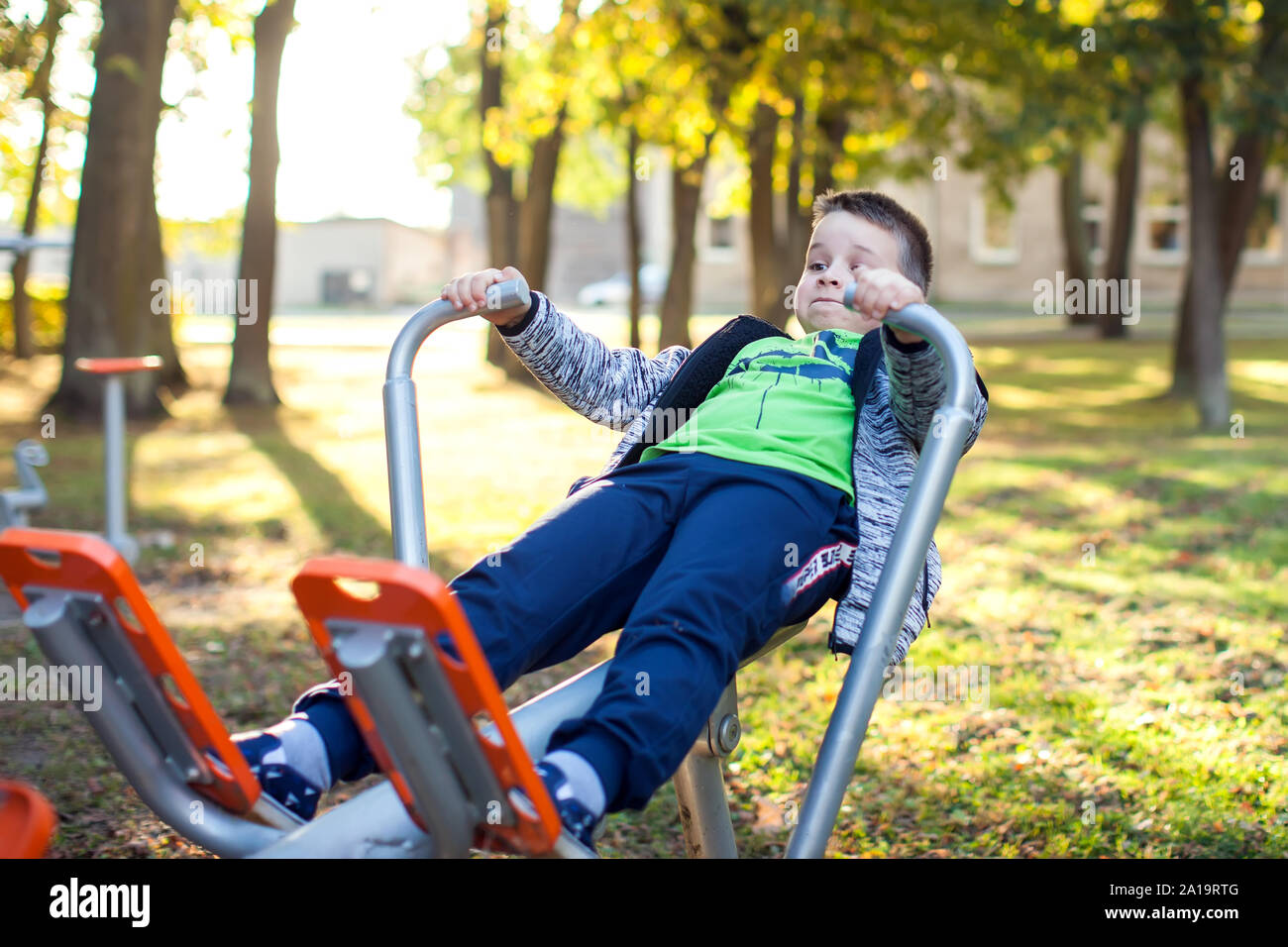 Kid boy does workout on trainer equipment outdoor. Children, activity ...