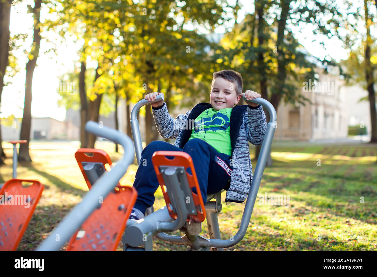 Kid boy does workout on trainer equipment outdoor. Children, activity ...